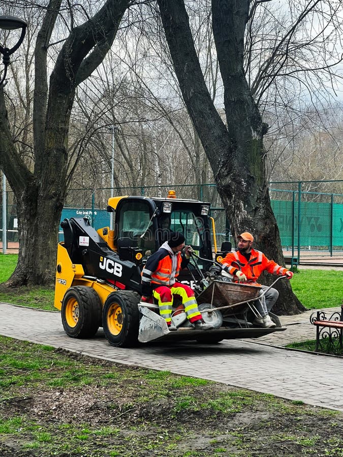 Workers Operating Heavy JCB Machinery Outdoors in a Park during ...