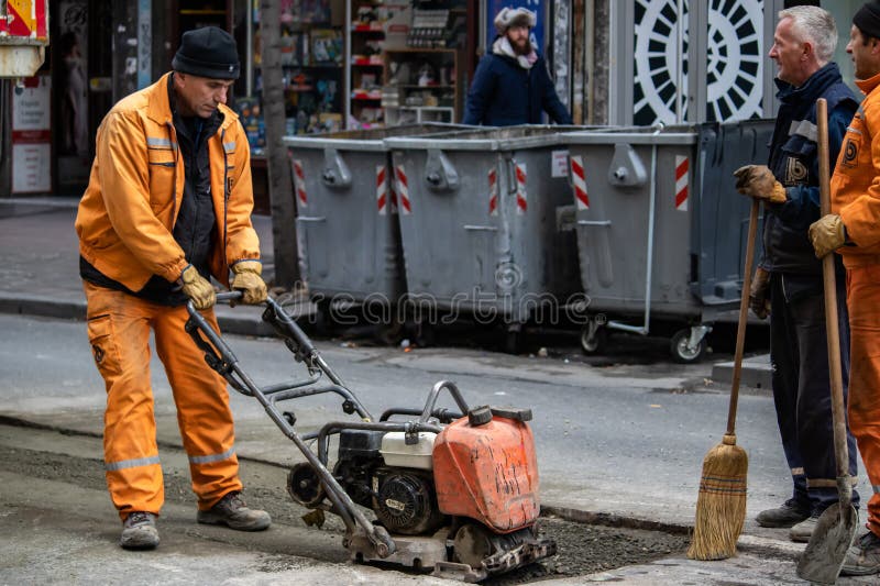 Workers in Orange Uniforms and Protection Equipment Fixing and Patching ...
