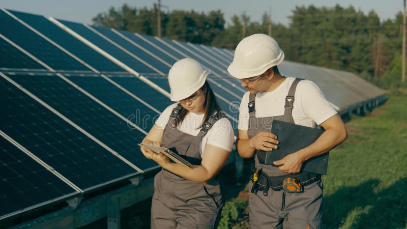Workers in Overalls Walk Around the Solar Panel Area and Analyze Data ...