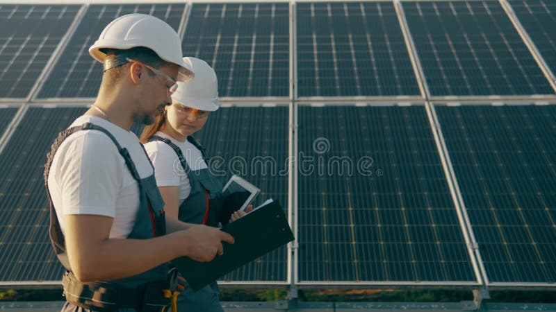 Workers in Overalls Walk Around the Solar Panel Area and Analyze Data ...