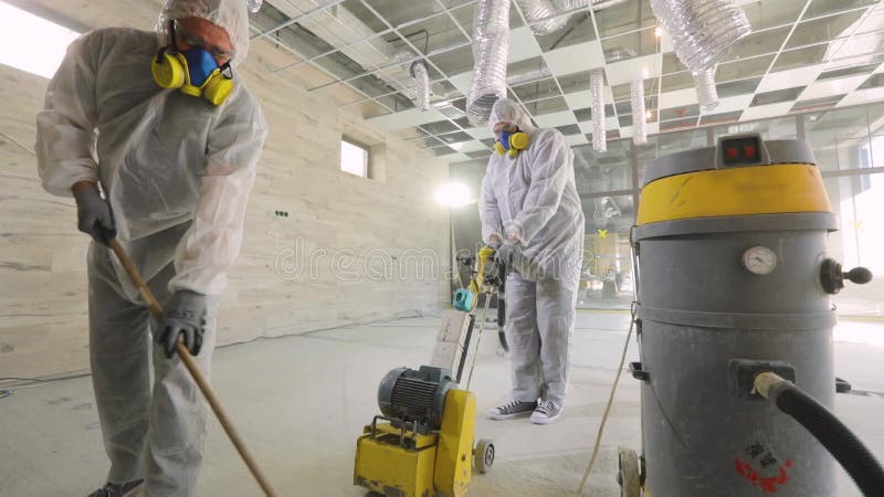 Workers in Protective Suits are Grinding the Concrete Floor. Working ...