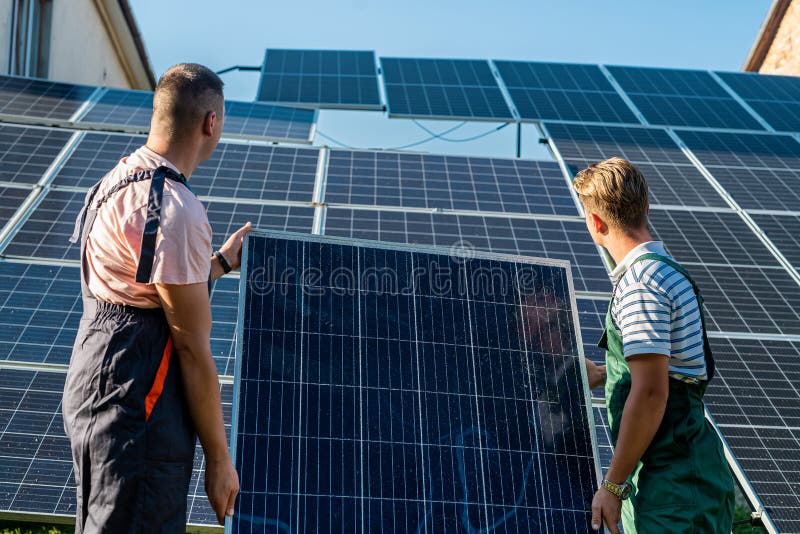Workers in Protective Uniform Carrying Solar Panel for Installation at ...