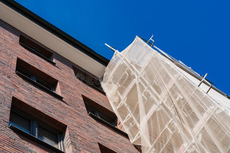 Construction Work on a Brick Building with Scaffolding Covered with ...