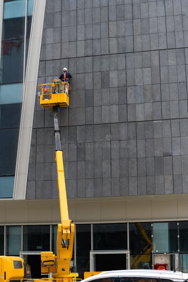 Workers Repairing the Outside of Commercial Building Vertical ...