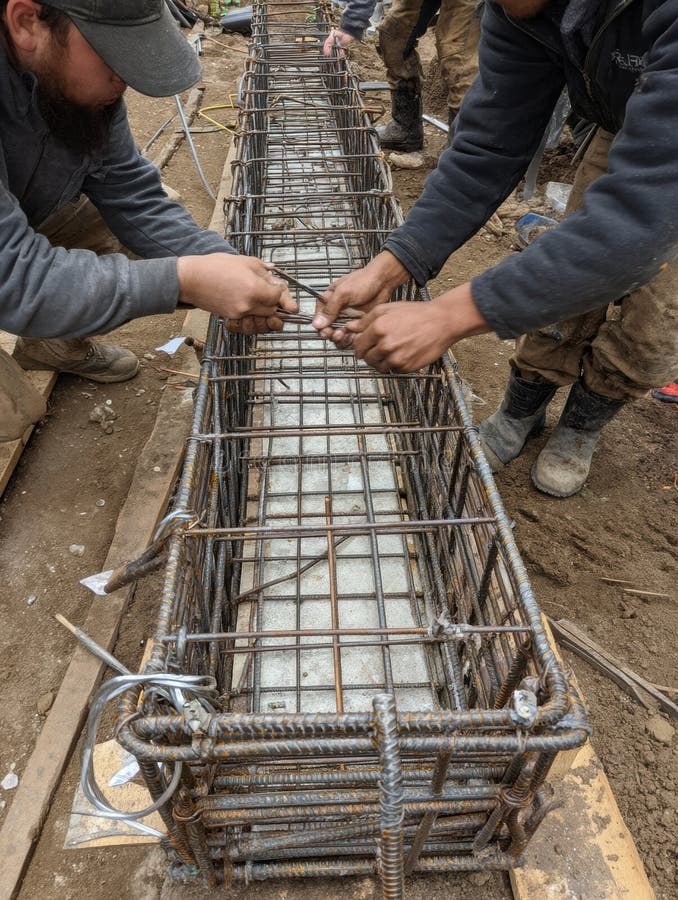Workers Secure Rebar Frame with Wire Ties during Construction on a ...