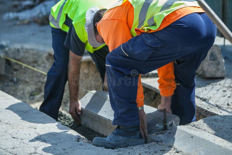 Workers with Special Uniforms Installing a Sidewalk in a Hole Filled ...