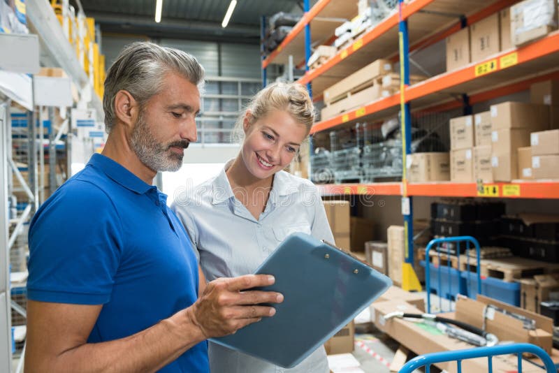 Workers in Storeroom Looking at Clipboard Stock Photo - Image of ...