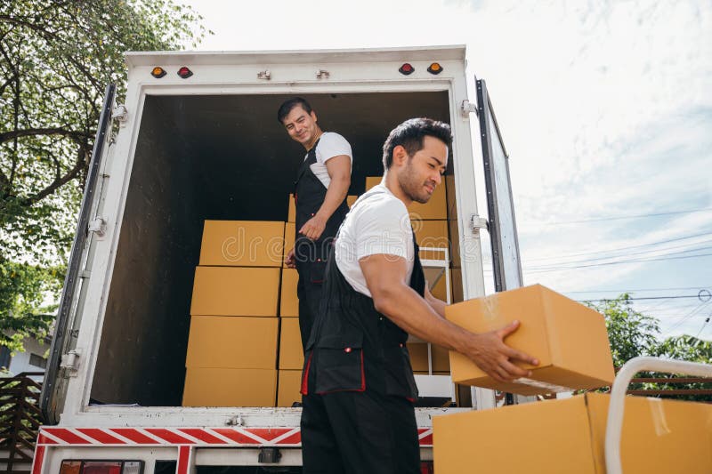Delivery Men Unload Boxes from a Van. Movers in Uniform Work Together ...