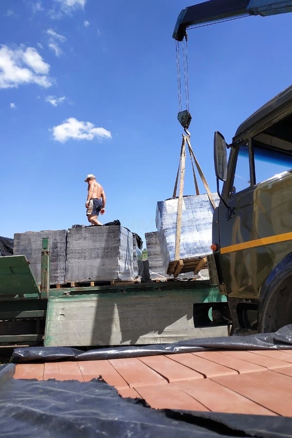 Workers Unload Pallets with Bricks by Means of the Crane of Automobile ...