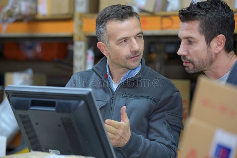 Workers Using Digital Devices in Warehouse on Desk Stock Image - Image ...