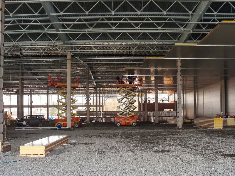 Workers are Using Scissor Lifts To Install Ceiling Panels Inside a New ...