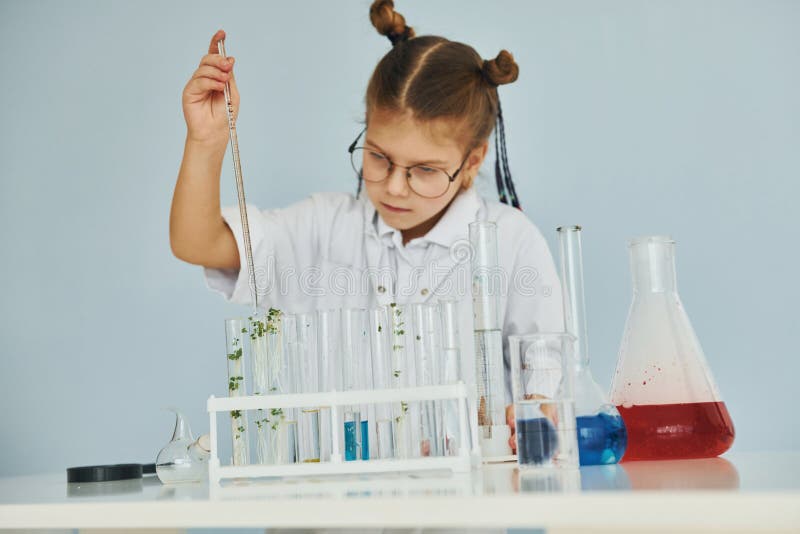Workes with Liquid that is in Test Tubes. Little Girl in Coat Playing a ...