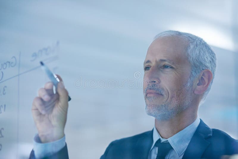 Working with Accuracy. a Mature Businessman Writing Figures on a Glass ...
