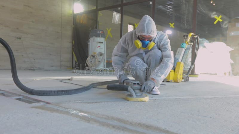 Concrete Floor Processing during Construction. Grinding a Concrete Floor with a Grinder. Builder ...