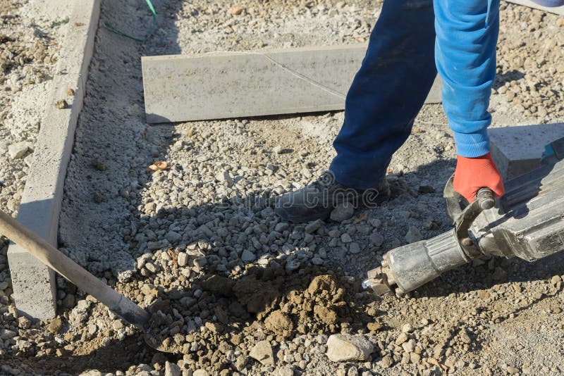 Working on a Construction Road, Workers Use a Jackhammer To Drill into ...