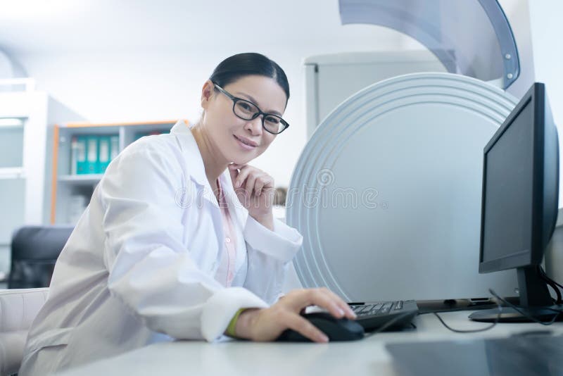Dark-haired Doctor in a White Robe Working on a Computer Having Her ...