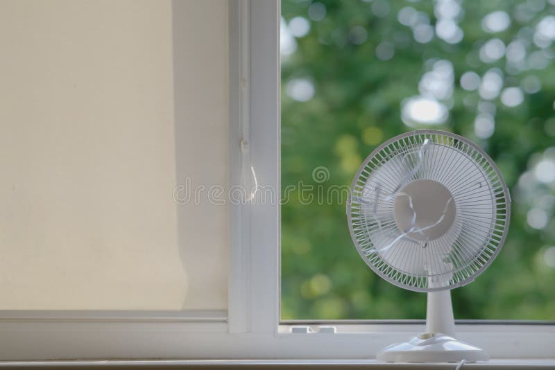 A Working Fan Stands on the Windowsill of an Open Window on a Hot ...