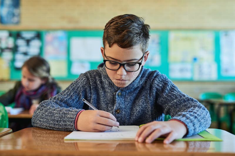 Working Hard To Complete His Worksheet. an Elementary School Boy ...
