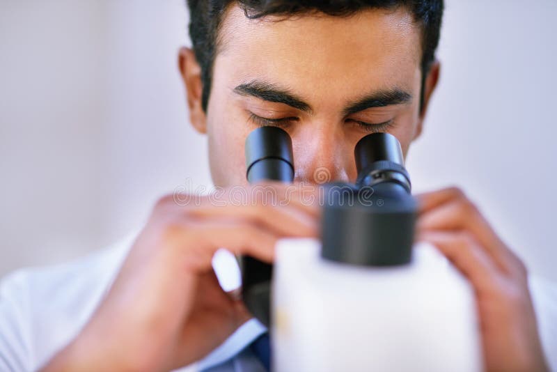 Working Hard To Find Results. a Lab Technician Using a Microscope while ...