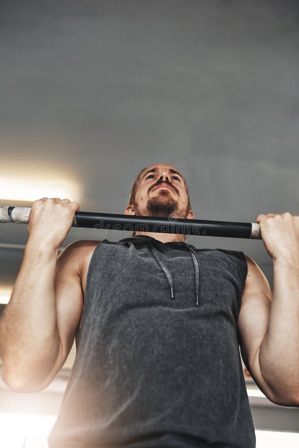 Working on His Upper Body Strength. a Young Man Doing Pull Ups in a Gym ...