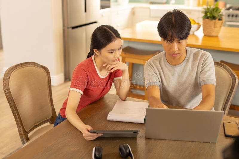 Working from Home, Asian Brother and Sister Using Laptop and Tablet at Kitchen Table Stock Photo ...