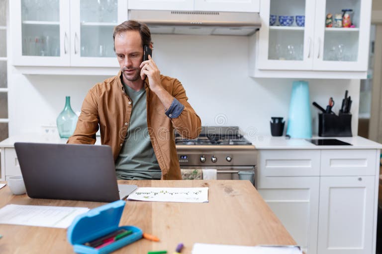 Working from Home, Man Using Laptop and Talking on Phone in Kitchen ...