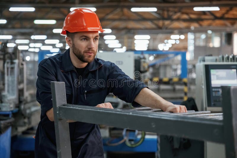 Working with Machinery. Factory Worker is Indoors with Hard Hat Stock ...