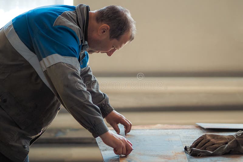 Working Man Works at Workbench in Workshop. Man in Overalls Measures ...
