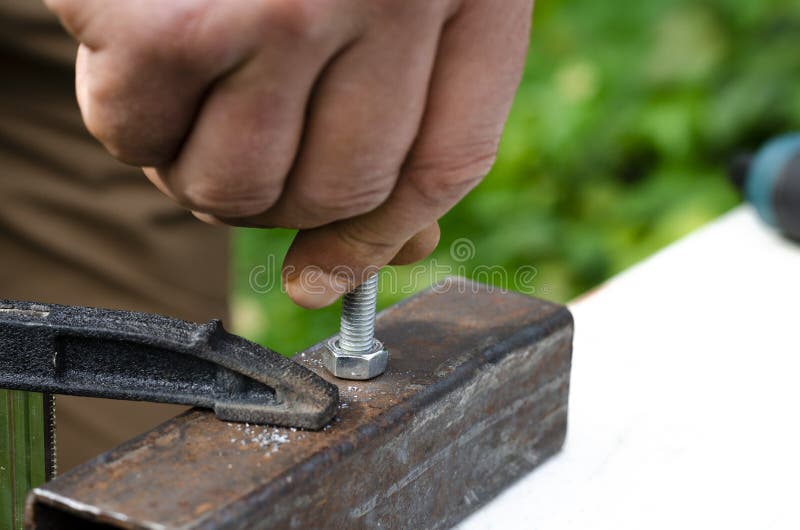 Working with Metal. a Man& X27;s Hand Screws a Bolt into a Metal Nut ...