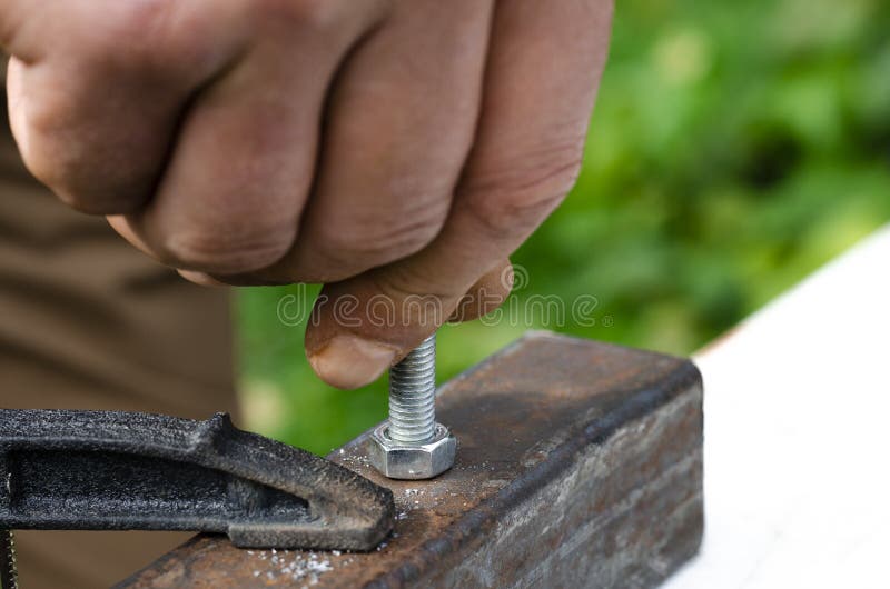 Working with Metal. a Man& X27;s Hand Screws a Bolt into a Metal Nut ...
