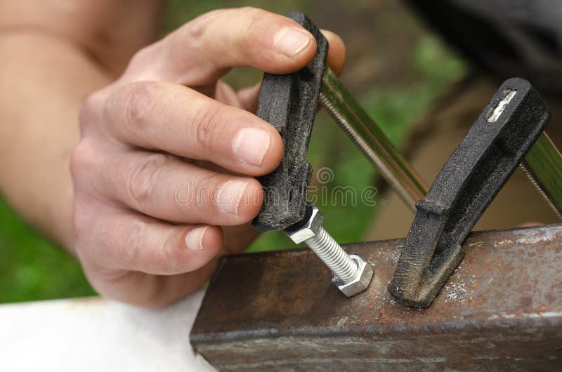 Working with Metal. a Man& X27;s Hand Screws a Bolt into a Metal Nut ...