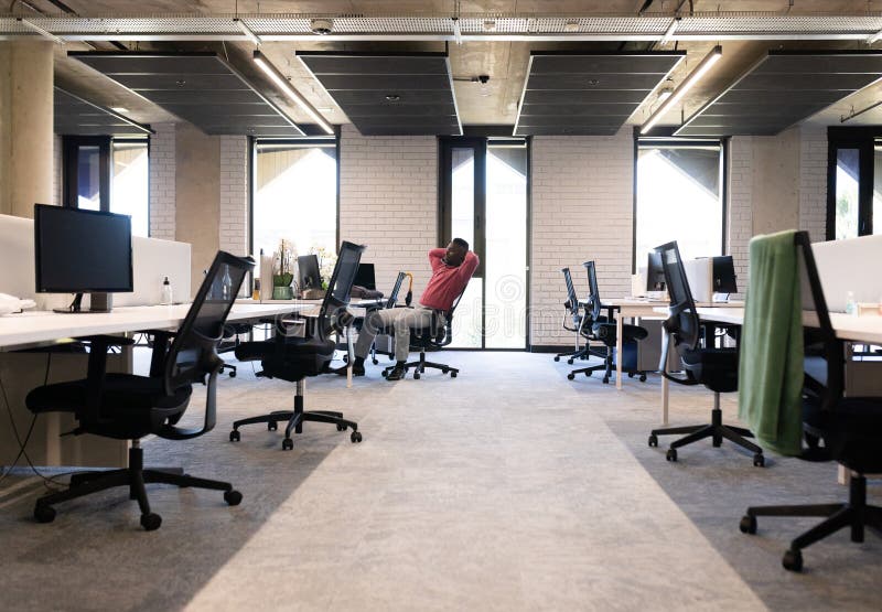 Working in Modern Office, Man Stretching at Desk with Computer Monitors ...