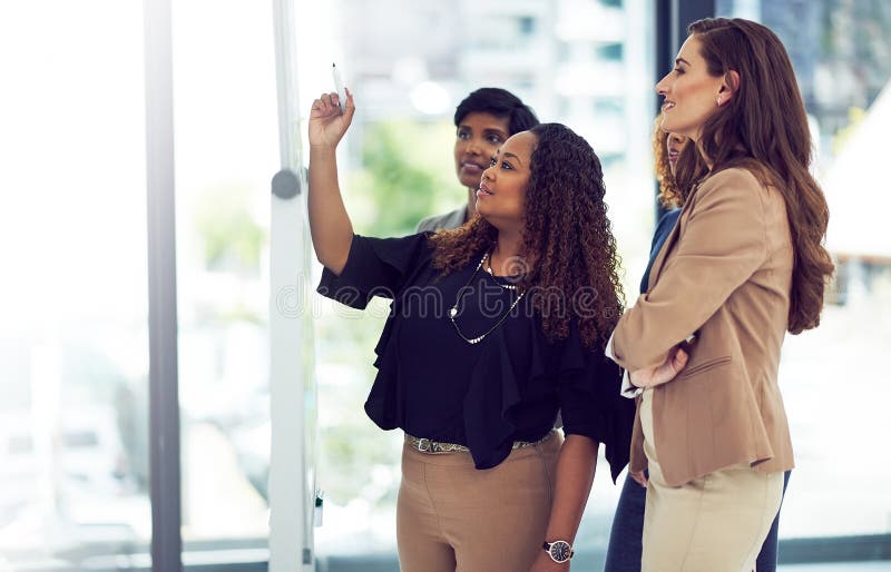 Working Out a Plan. a Group of Businesswomen Working on a Whiteboard in ...