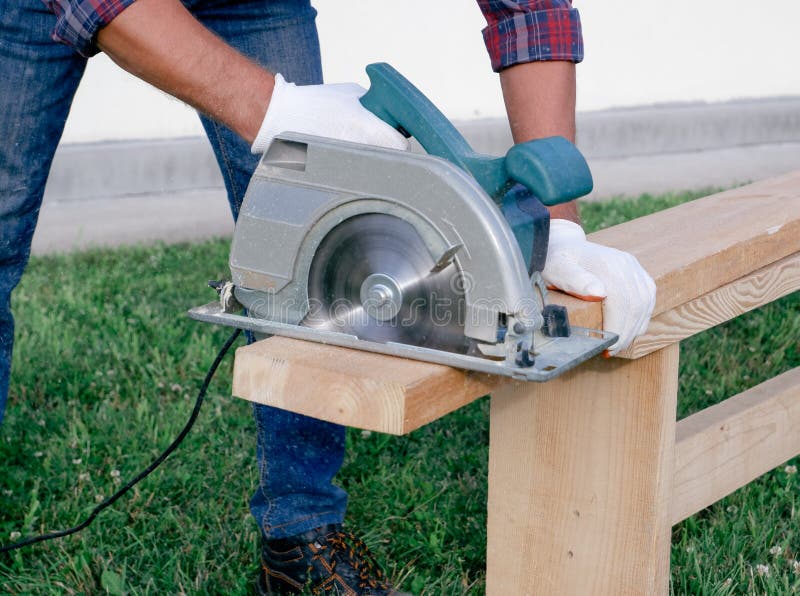 Working with a Power Tool. a Builder is Sawing a Board at the ...