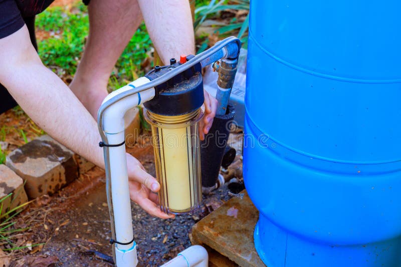 Working on a Water Filtration System with a Yellow Filter in a Backyard ...