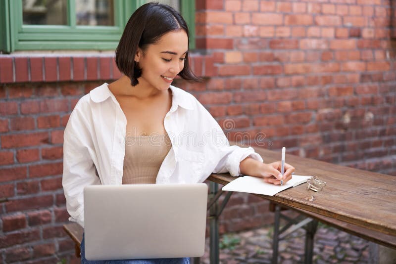 Working Woman Sitting Outdoors in Cafe, Looking at Laptop and Making ...