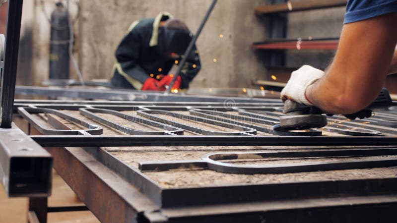 A Worker Grinds Metal Products with a Grinder Against the Background of ...