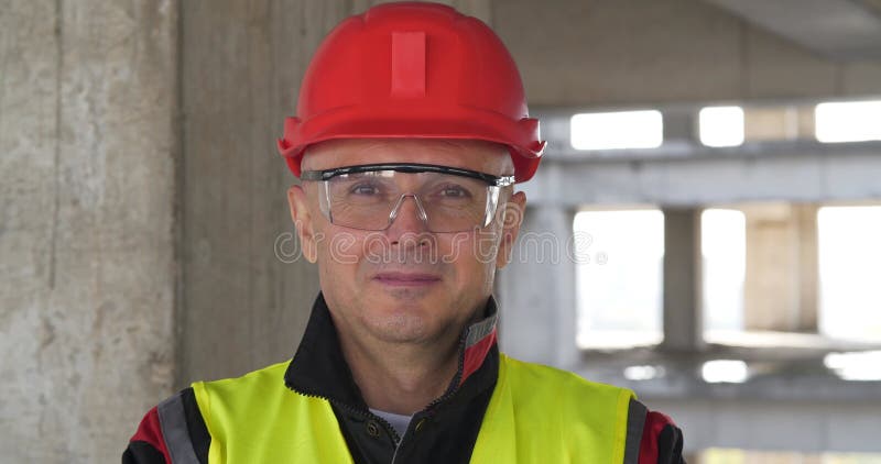Workman in Googles and Hard Hat Stands at Construction Site and Looks ...