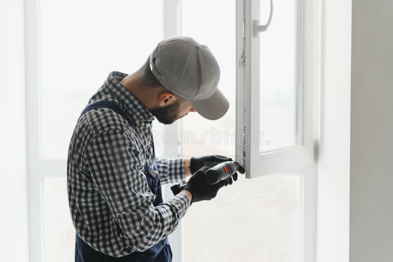 Workman in Overalls Installing or Adjusting Plastic Windows in the ...