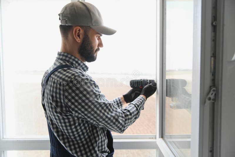 Workman in Overalls Installing or Adjusting Plastic Windows in the ...