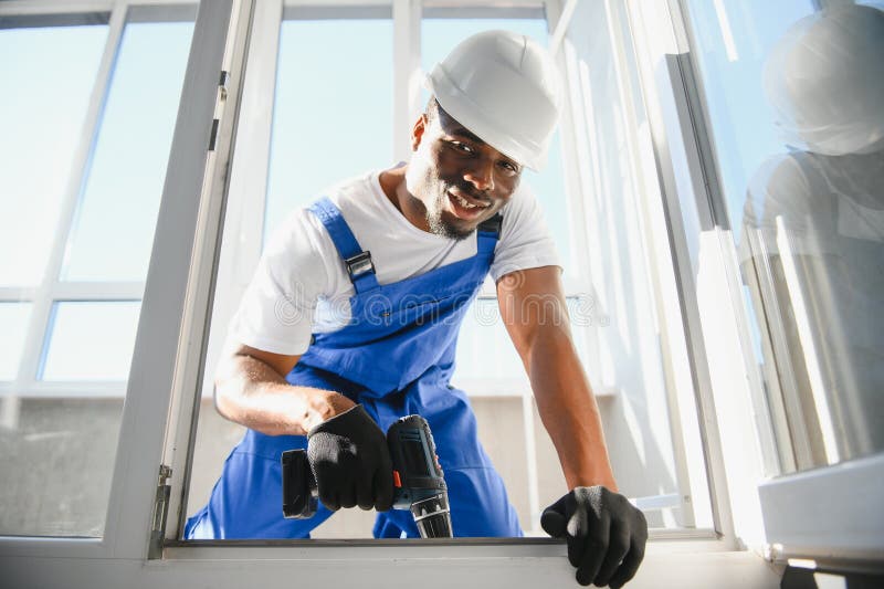Workman in Overalls Installing or Adjusting Plastic Windows in the ...