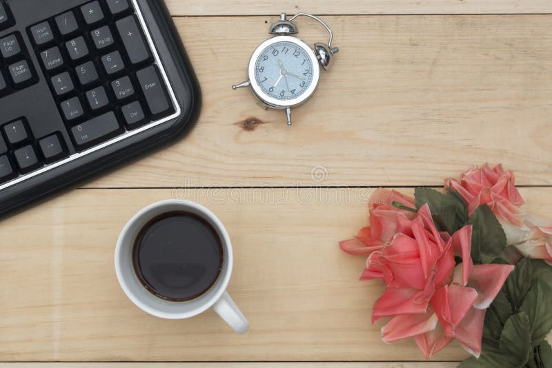 Workplace with Keyboard, Alarm Clock, Coffee and Flowers on Wood Table ...