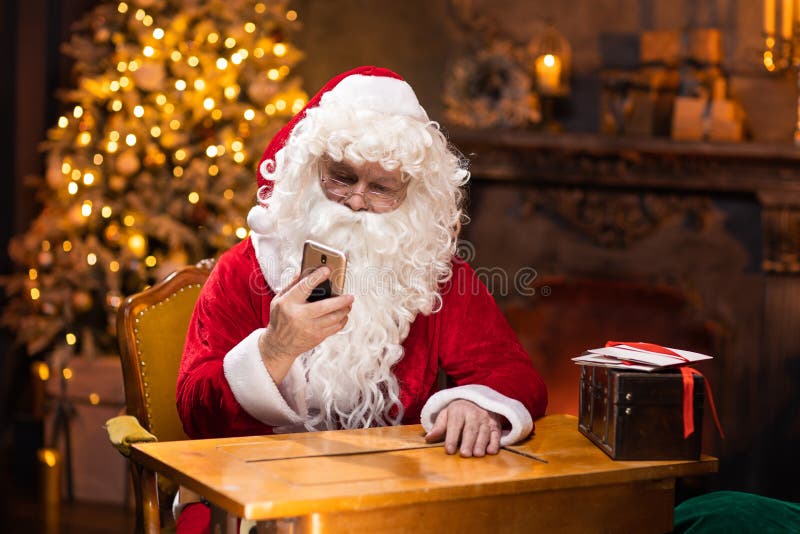 Workplace of Santa Claus. Cheerful Santa is Working Using Smartphone ...