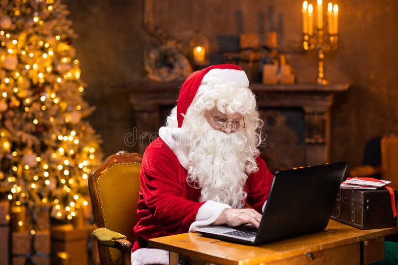 Workplace of Santa Claus. Cheerful Santa is Working on the Laptop while ...