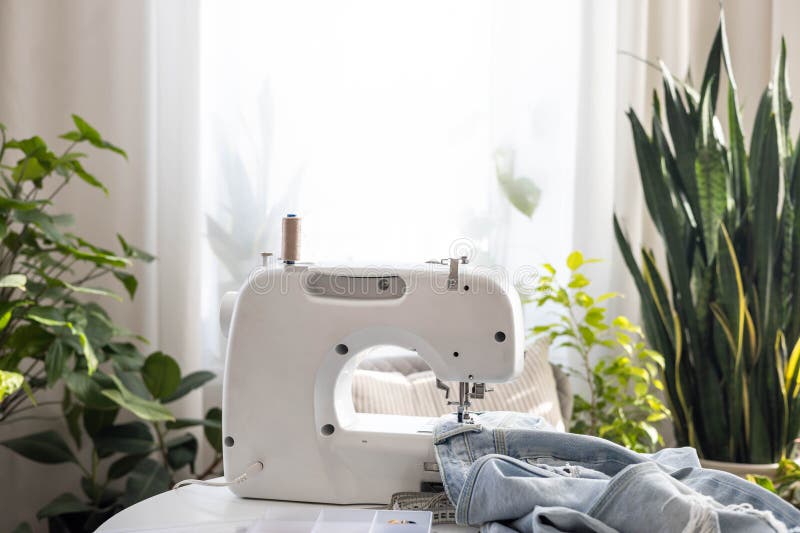 Workplace with a Sewing Machine. There are Old Blue Jeans on the Table ...