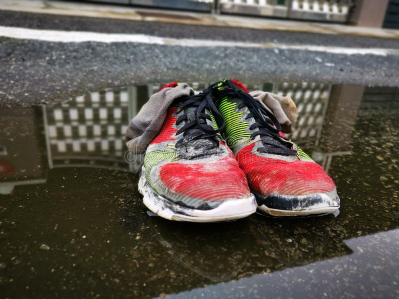 Worn Out Sneaker and Stocking on the Roadside`s Puddle. Stock Image ...