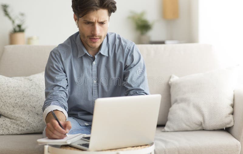 Worried Young Man Taking Notes Using Laptop Sitting on Sofa Stock Image ...