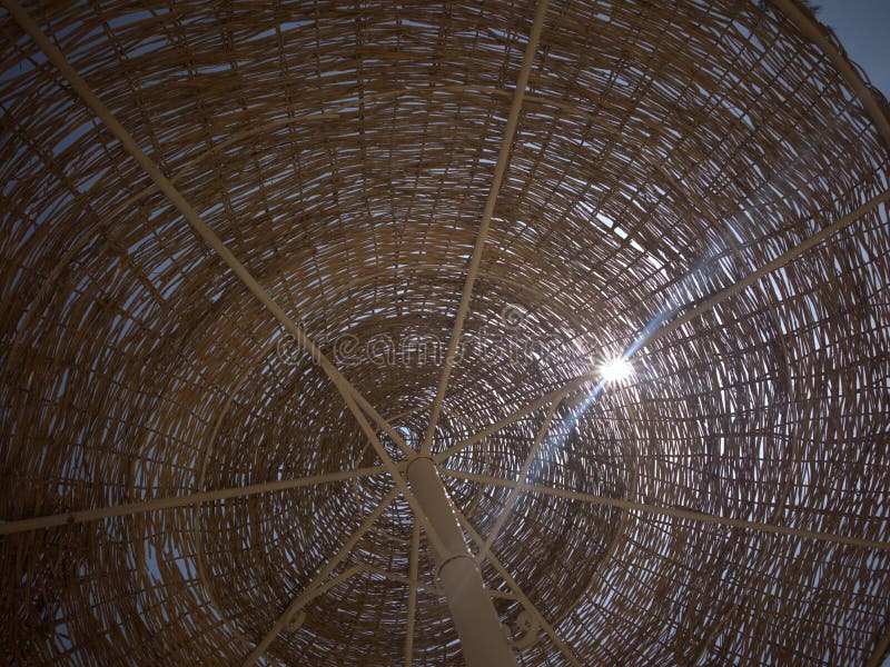 Close-Up View of a Straw Parasol Silhouetted Against the Sun Stock ...