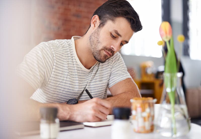 The Write Stuff. Shot of a Handsome Young Man Writing in a Notebook ...