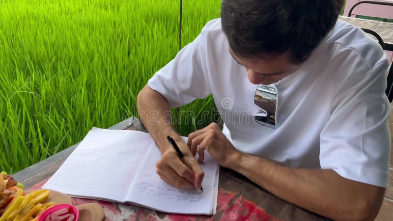 A Writer Working Outdoors at a Cafe in the Rice Field. Man Writing Down ...